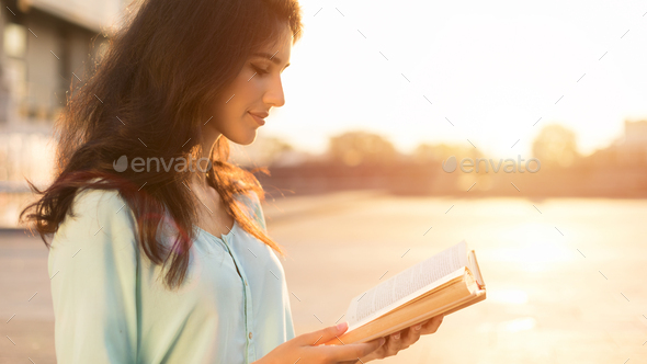 Student girl reading book outdoors, enjoying sunset Stock Photo by ...