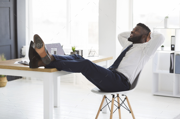 Joyful young manager relaxing on chair in white modern office Stock ...