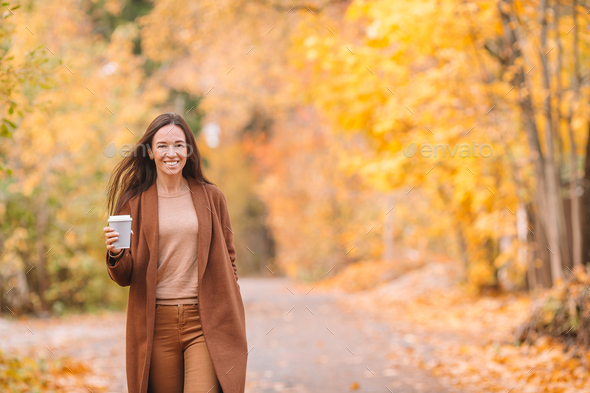Fall concept - beautiful woman drinking coffee in autumn park under ...