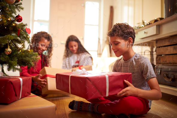 Excited Children Opening Presents By Tree On Christmas Morning Stock ...