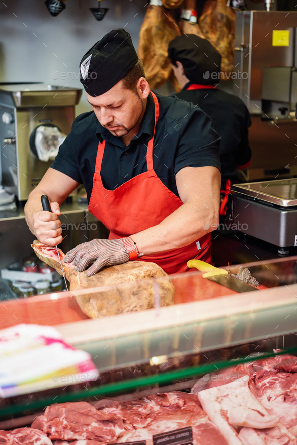Butcher boning a ham in a modern butcher shop Stock Photo by javi_indy