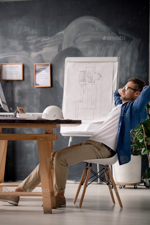Relaxed engineer sitting on chair by table and watching video on ...