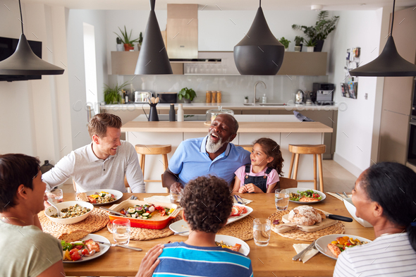 Multi-Generation Mixed Race Family Eating Meal Around Table At Home ...