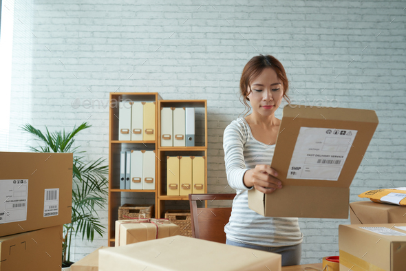 Ethnic woman opening box in post office Stock Photo by DragonImages