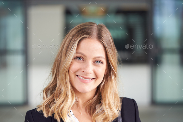 Head And Shoulders Portrait Of Smiling Businesswoman Standing In Lobby ...