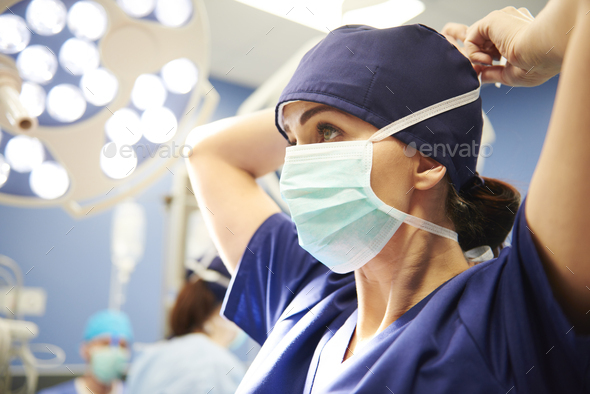 Side view of young female surgeon tying her surgical mask Stock Photo ...