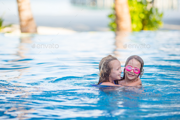 Adorable little girls playing in outdoor swimming pool on vacation ...