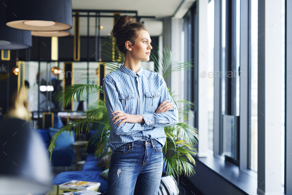 Focused woman looking through window in the office Stock Photo by ...