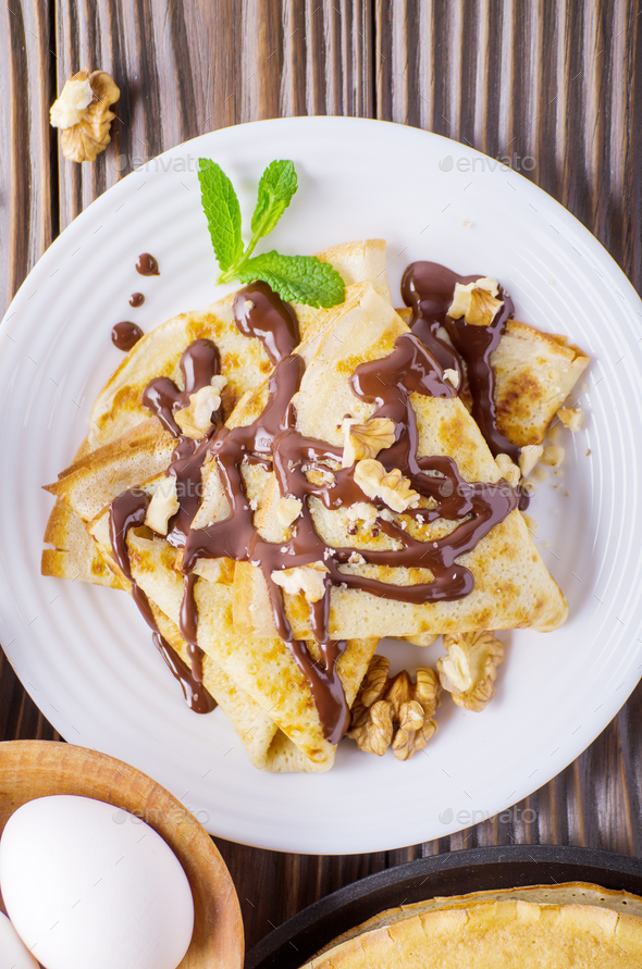 Flat lay French crepes with chocolate sauce walnuts eggs and flour on ...