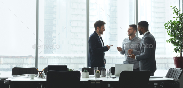 Businessmen talking by conference table in office, free space Stock ...