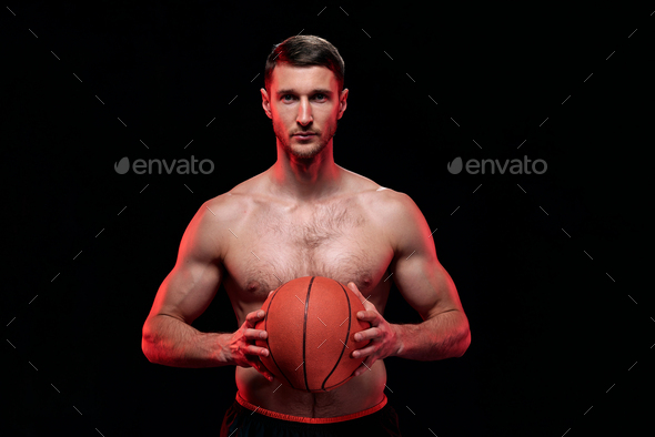 Young shirtless muscular basketball player holding ball by his chest ...