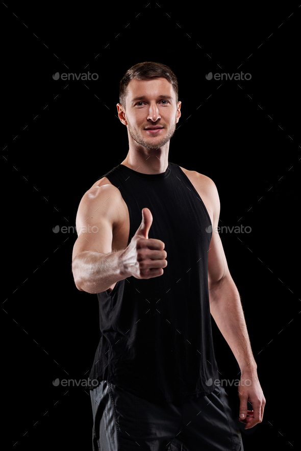 Happy young successful muscular athlete showing thumb up in isolation ...