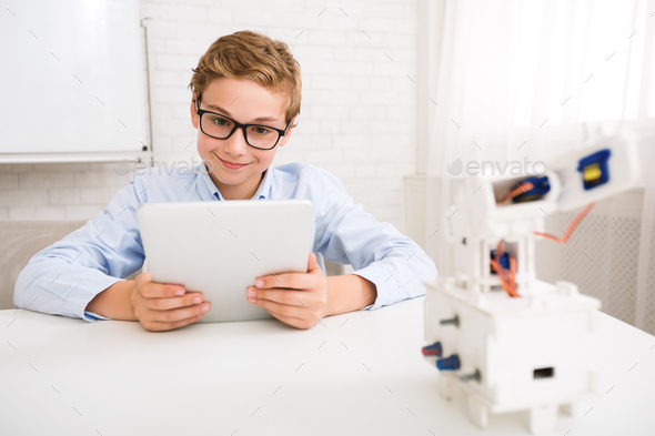 Smart boy programming robot with tablet at stem educational lesson ...