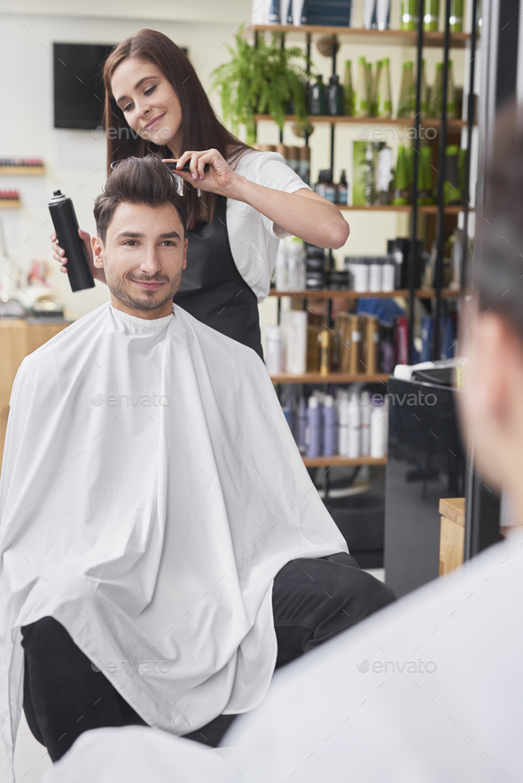 Smiling male customer sitting in hair salon Stock Photo by gpointstudio