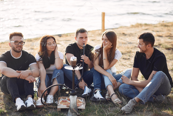 Young people eating pizza smoking hookah outside - Stock Image - Everypixel