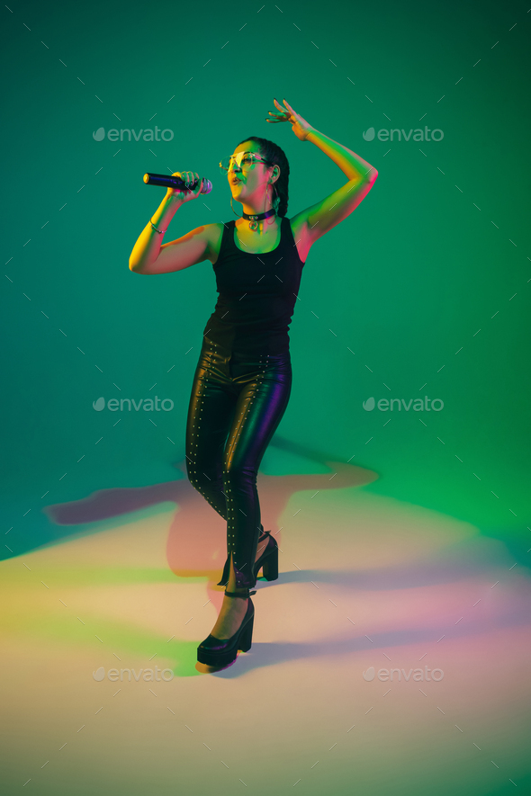 Caucasian female singer portrait isolated on green studio background in ...