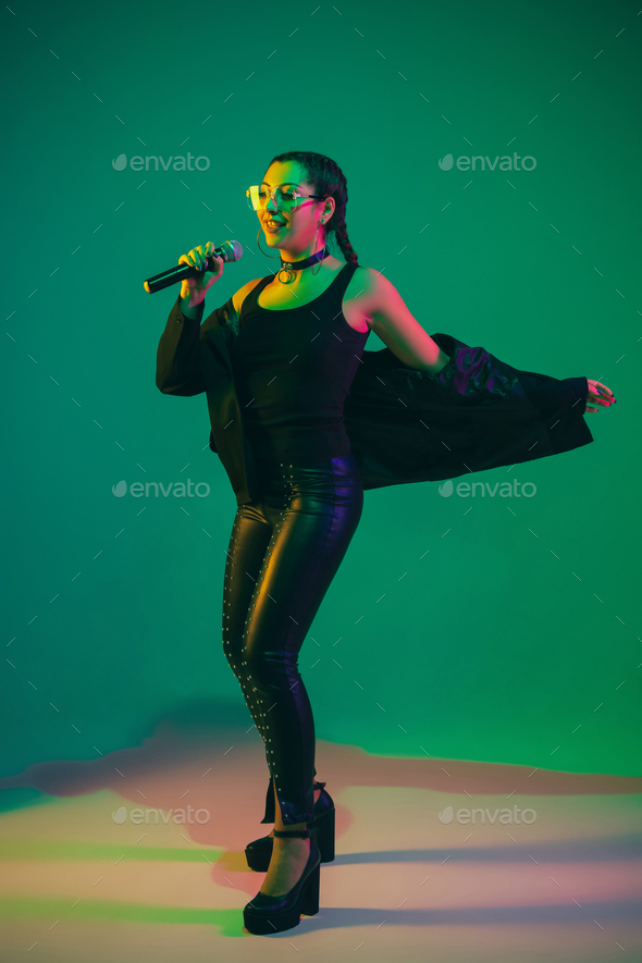 Caucasian female singer portrait isolated on green studio background in ...