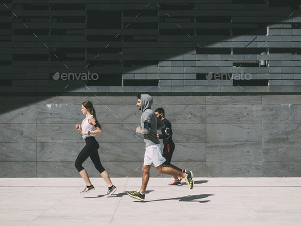 three friends athletes jogging in a modern building district Stock ...