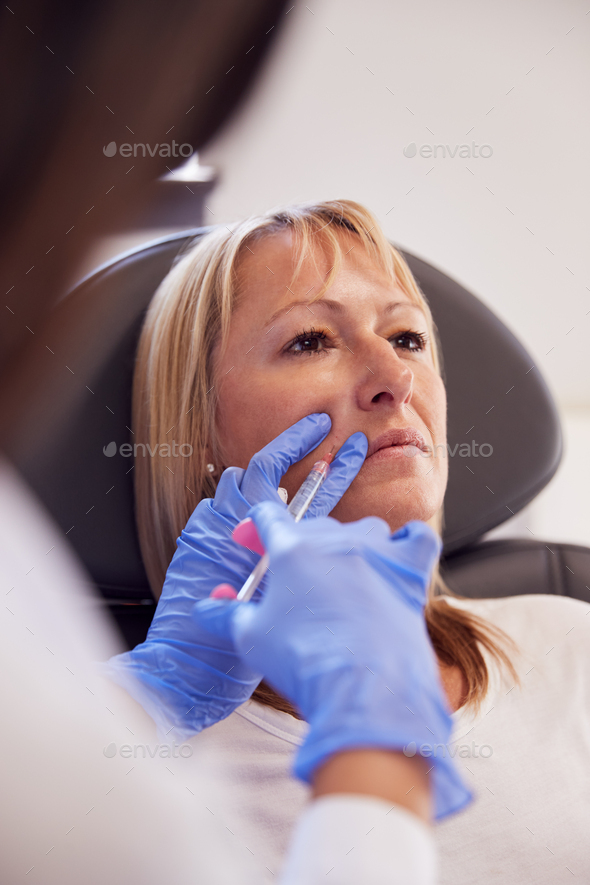 Mature Woman Sitting In Chair Being Give Botox Injection By Female ...