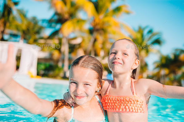 Adorable little girls playing in outdoor swimming pool on vacation ...