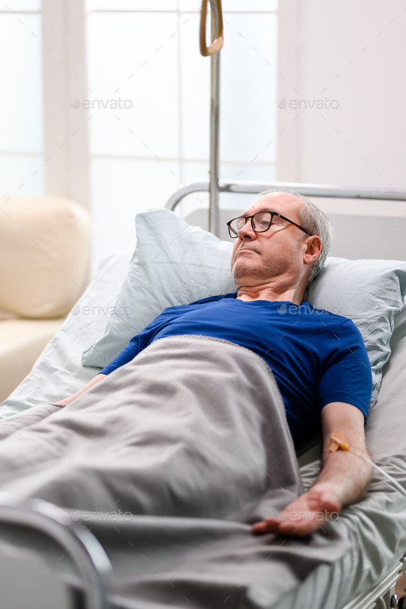 Retired old man in nursing home laying on bed Stock Photo by DC_Studio