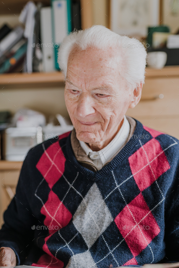 Old man looking at old albums with family photos Stock Photo by Macro_Media