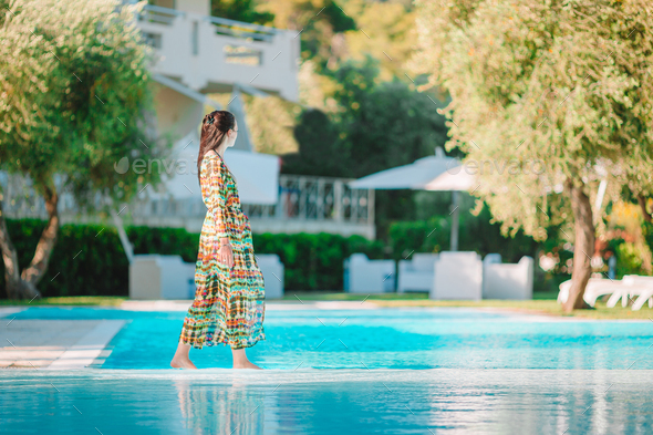 Woman relaxing by the pool in a luxury hotel resort enjoying perfect ...