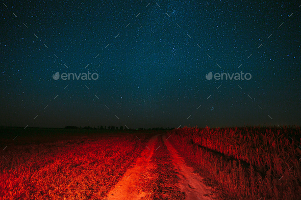 Night Starry Sky With Glowing Stars Above Country Road Is Lit In Red ...