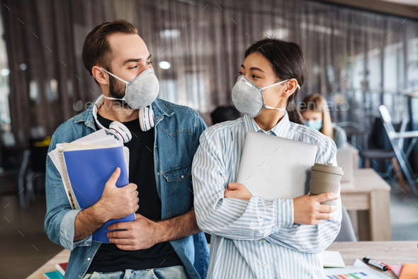 Photo of multinational students in medical masks standing at classroom ...
