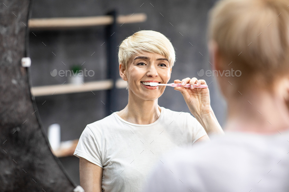 Lady Brushing Her Teeth Using Toothbrush Standing In Bathroom Indoors ...