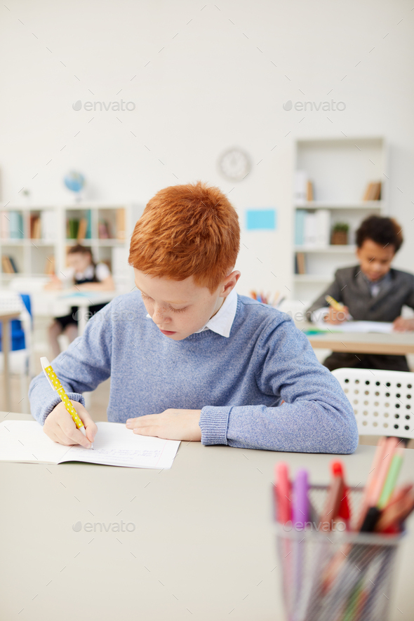 Schoolboy doing paper work Stock Photo by AnnaStills | PhotoDune