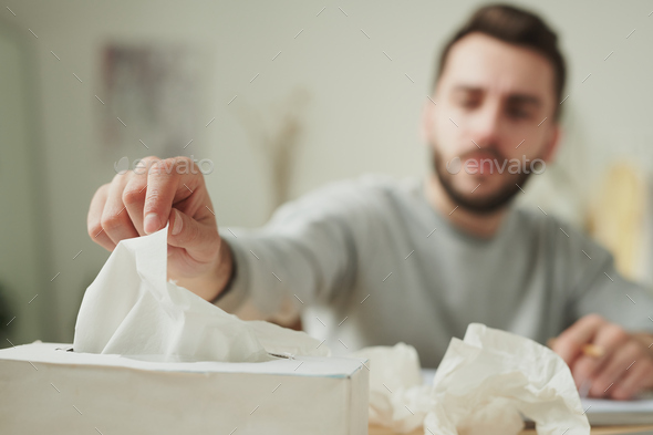 Hand of sick businessman taking paper tissue from box while sitting by ...