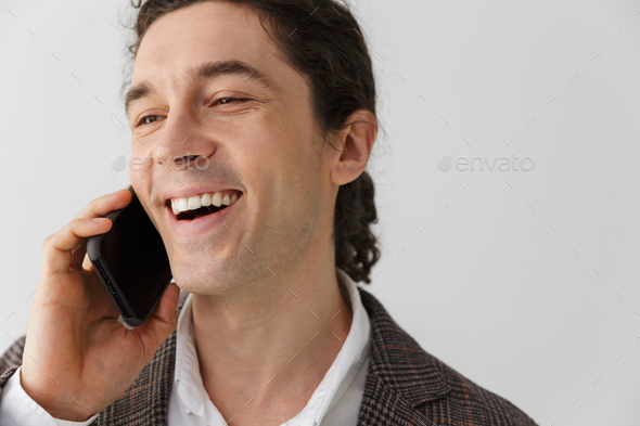 Image of funny handsome man in jacket laughing and talking on cellphone ...