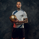 Bold and handsome soccer player holding a golden soccer ball Stock ...