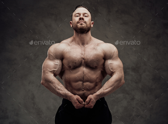 Athletic man isolated on a grey background is showing his chest muscle ...
