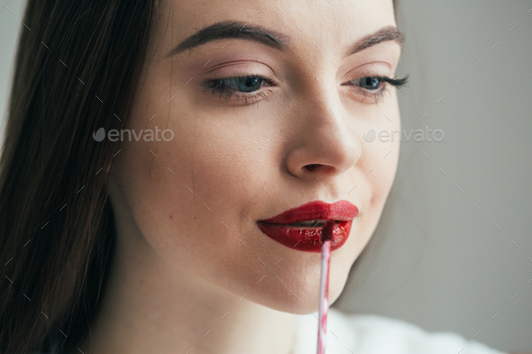 Closeup shot of woman paint her lips by cosmetic brush lipstick on lips ...