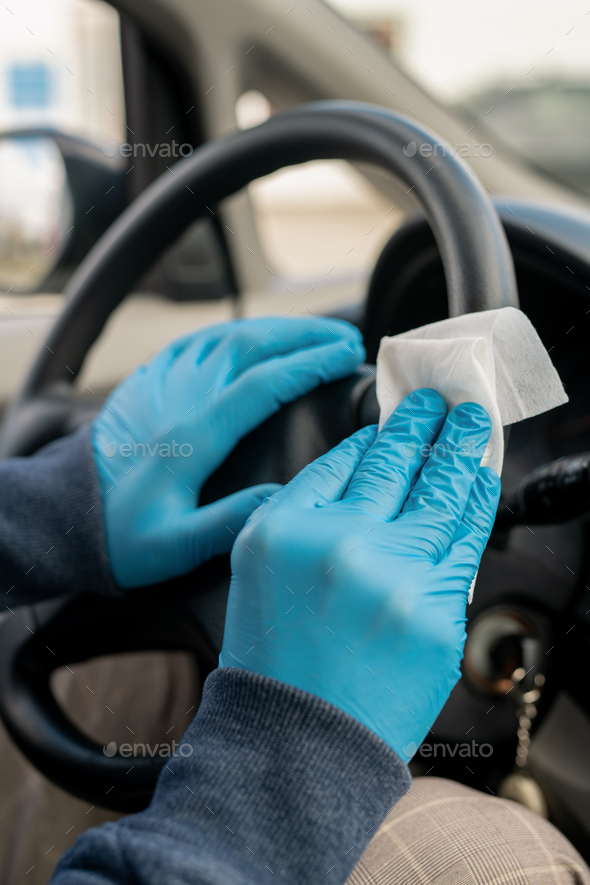 Gloved hands of young man cleaning steer with wet wipe before driving ...