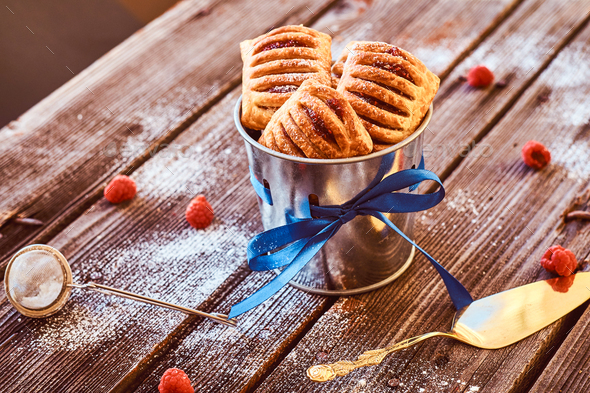 Puff pastry with jam in a bucket decorated with a blue ribbon on wooden ...