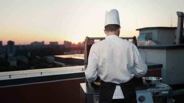 A professional Chef prepares a barbecue on the rooftop of a skyscraper ...