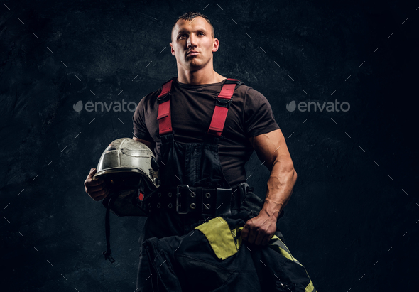 Portrait of a brutal muscular fireman holding a helmet and jacket Stock ...