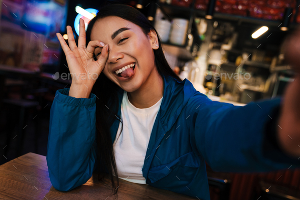 Photo of joyful nice asian woman gesturing ok sign while taking selfie ...