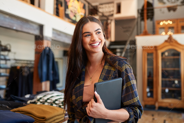 Smiling Female Owner Of Fashion Store Standing In Front Of Clothing ...