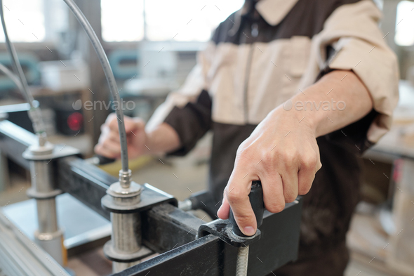 Hand of worker turning handle of industrial machine while fixing ...
