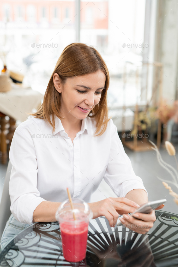 Happy young woman scrolling in smartphone while looking for curious ...