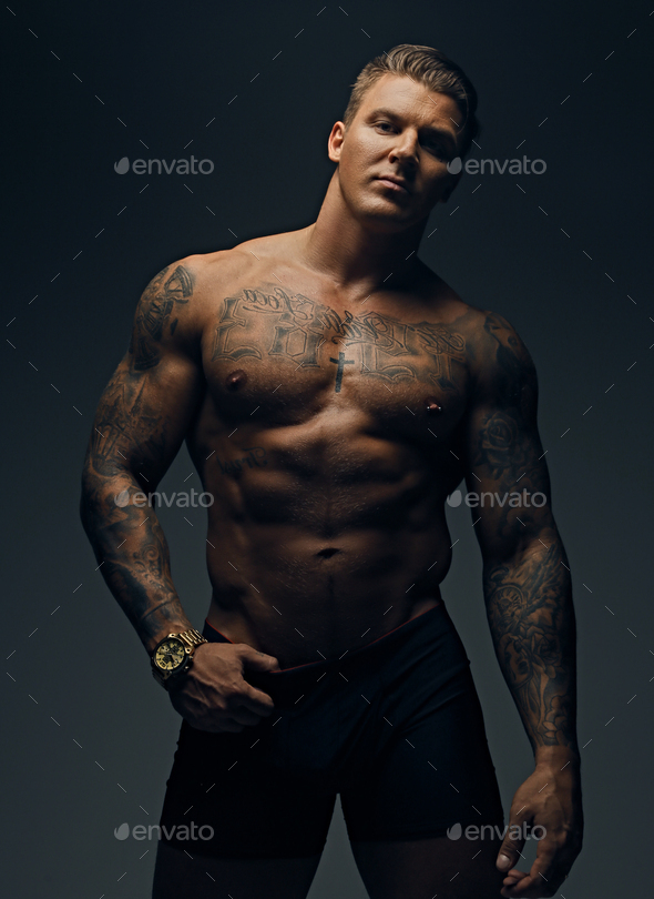Portrait of tattooed muscular male in a shadow. Stock Photo by fxquadro