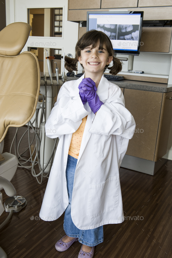 A portrait of a young Caucasian girl playing dress up in a dental ...