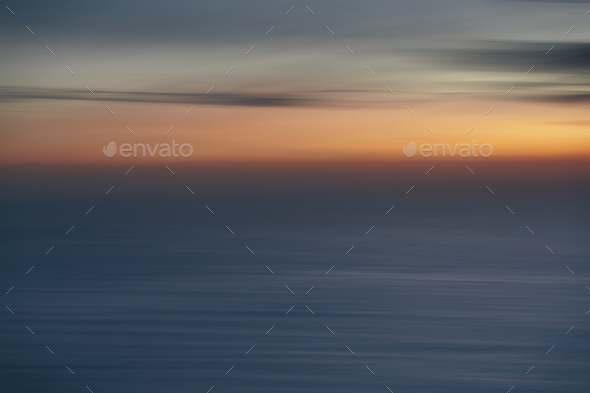 View out to sea over the ocean at dusk, the sunset light on the horizon ...