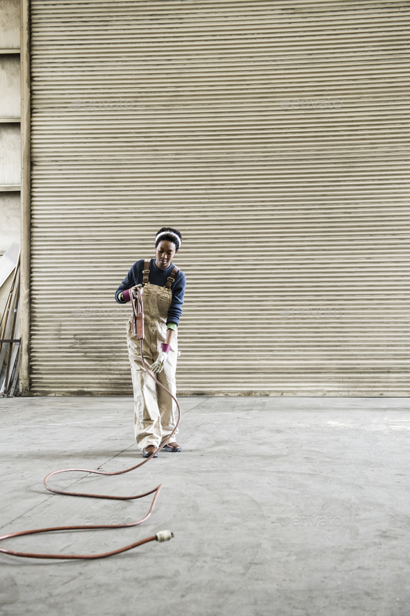 Black woman factory worker gathering tools together on the floor of a ...