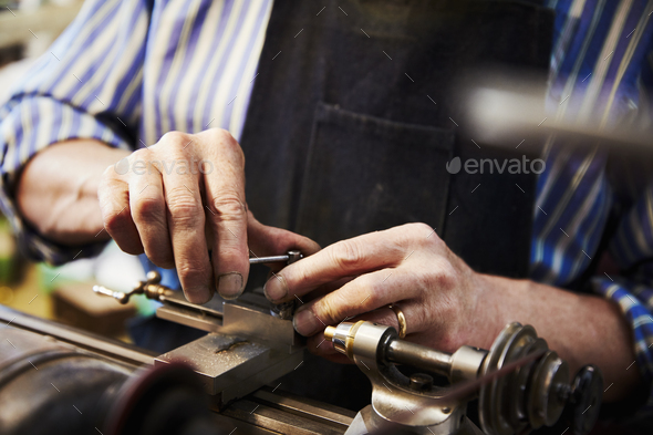 A clock maker and repairer working on the small parts of a clock using ...