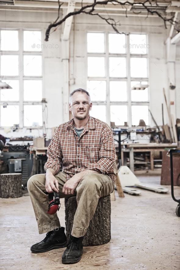 Caucasian man factory worker sitting on a stool in a woodworking ...